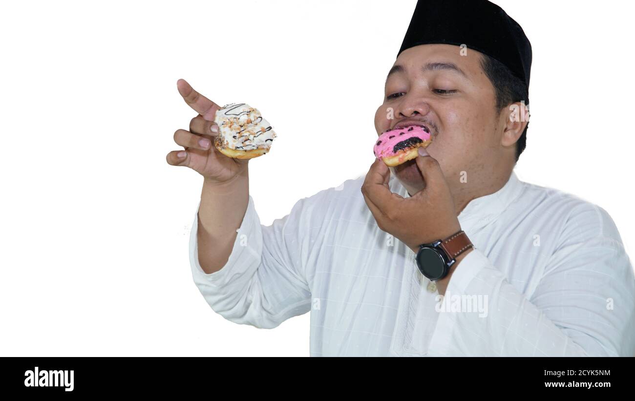 portraits of overweight or fat Asian Muslim men enjoy eating two donuts ...