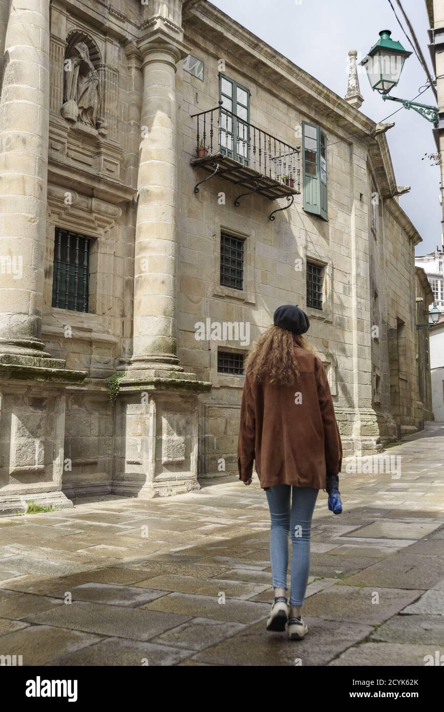 Vertical back view of a young hipster female tourist walking through an ...