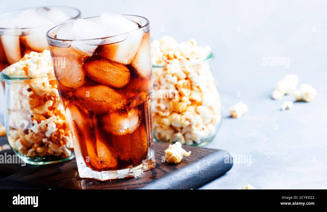 Sweet soda with ice cubes and caramel popcorn, gray background ...