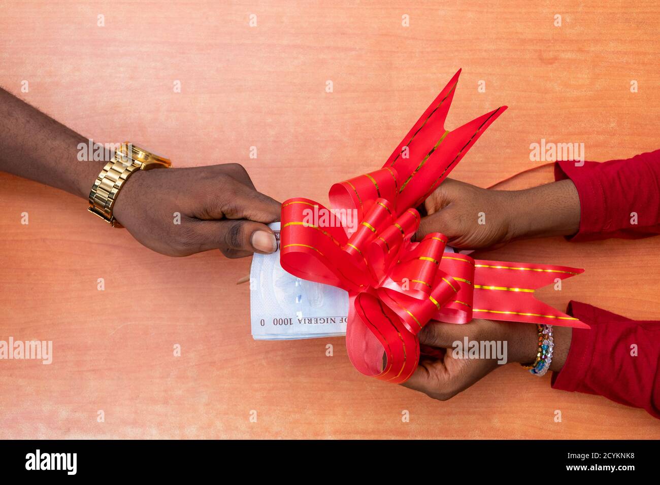 black man and woman holding some money wrapped with a red ribbon. cash ...