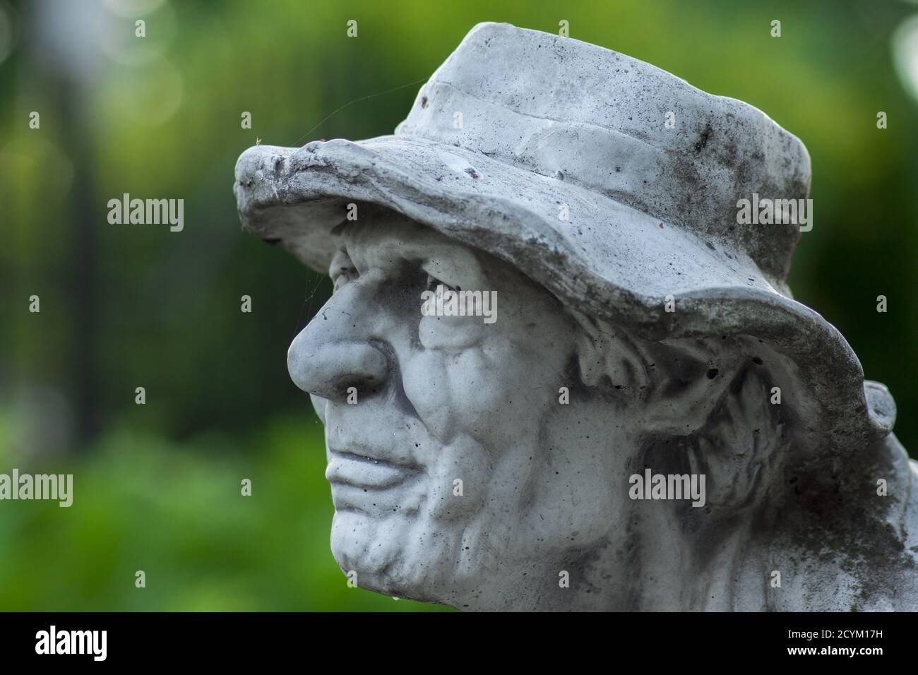 A plaster figure of an old and tired man standing in the backyard ...
