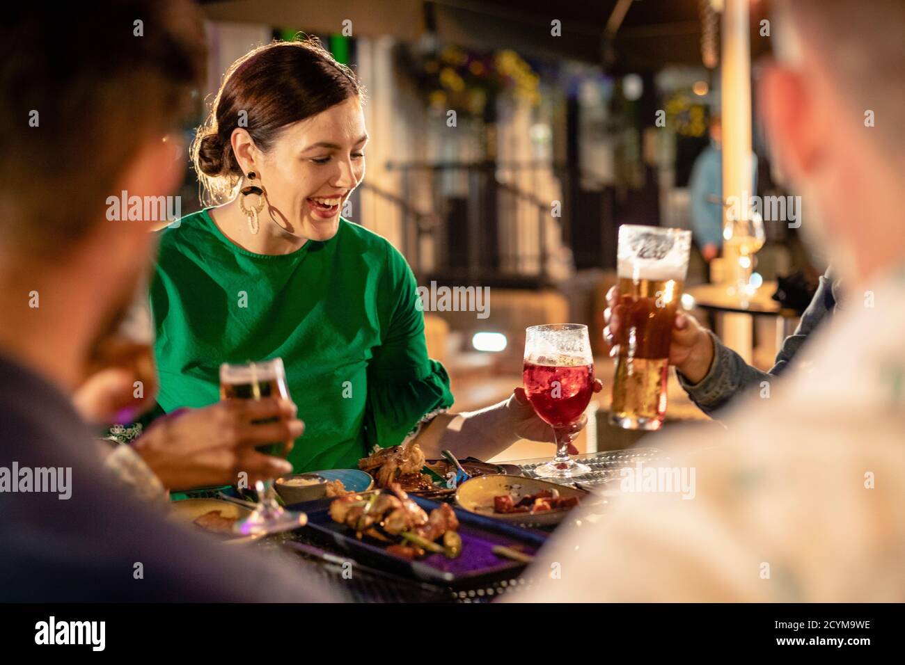 Friends drinking alcohol outdoors at a bar/restaurant, celebrating and ...