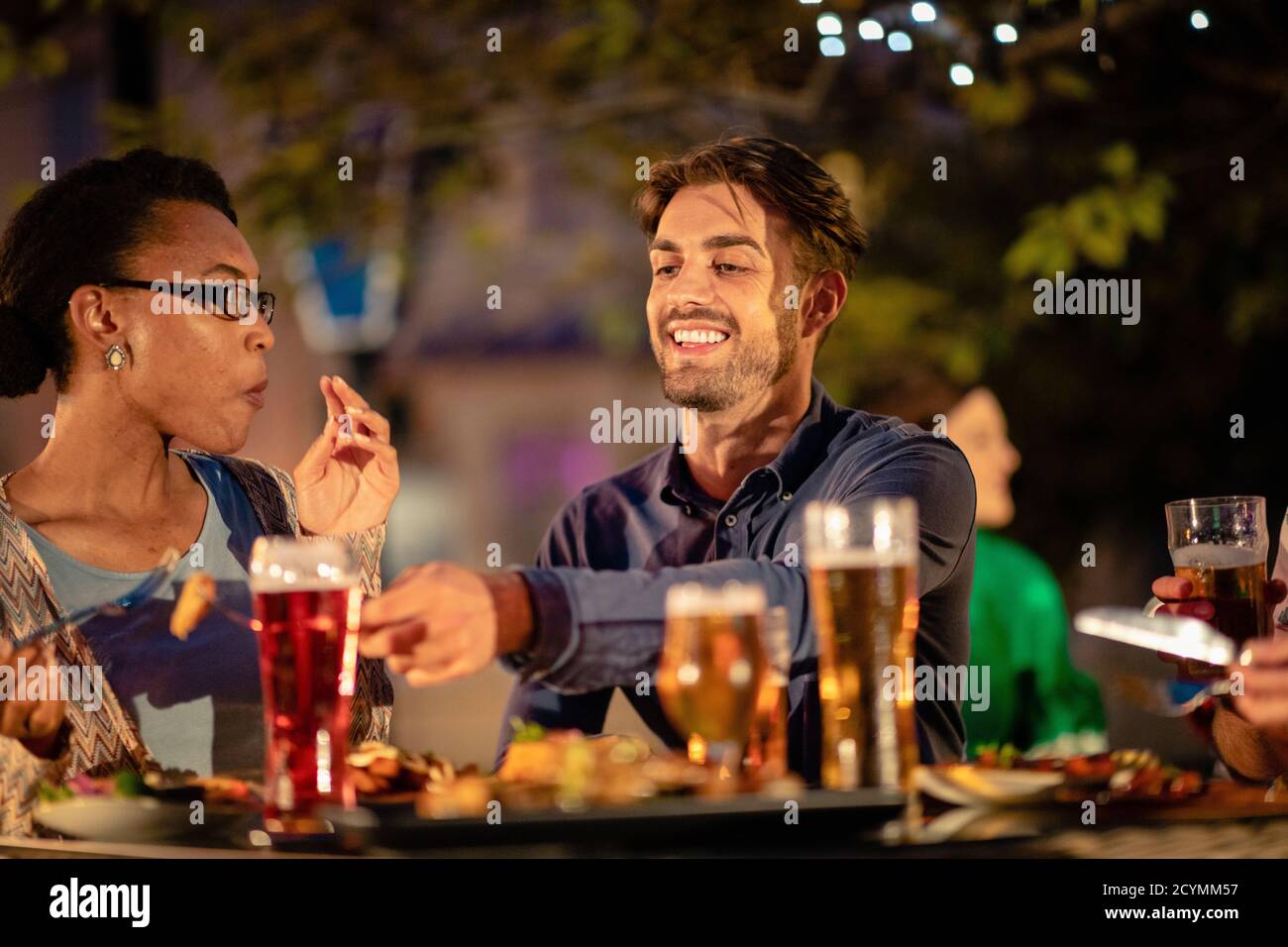 Friends drinking Alcohol outdoors at a bar/restaurant, celebrating and ...