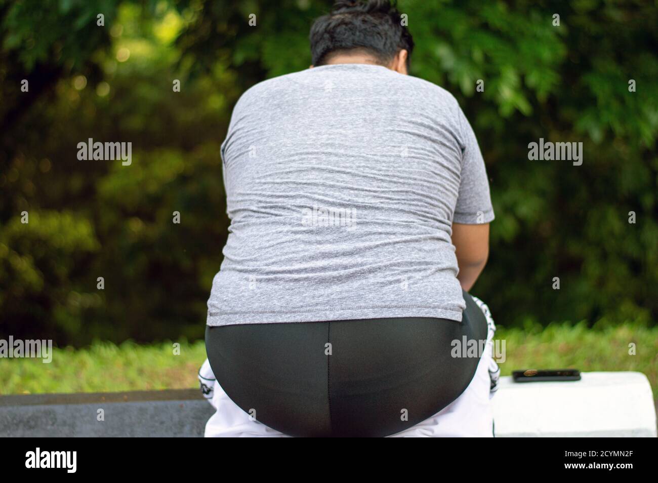 Asian young man with obesity sits and shows his pants that won't fit in ...