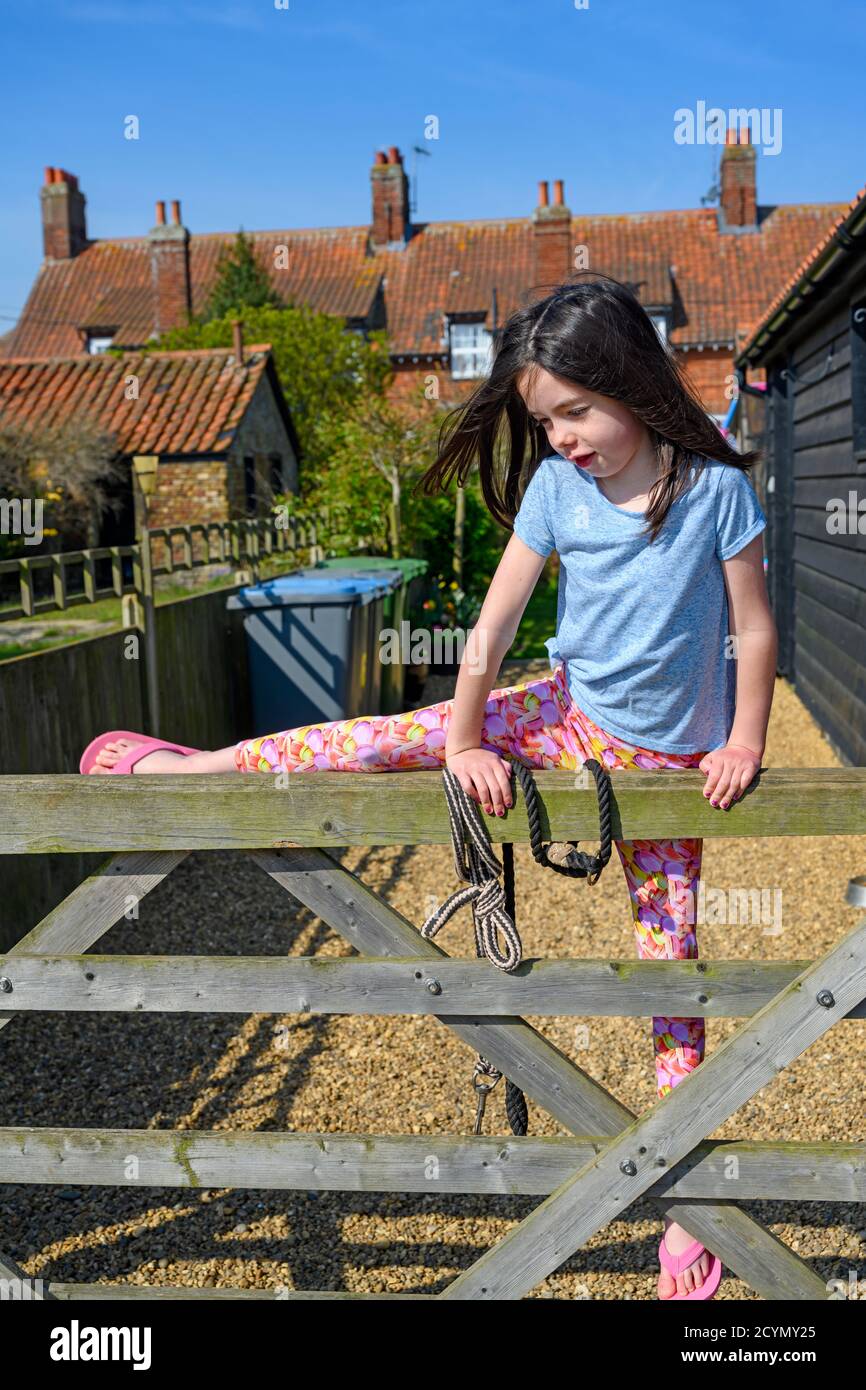 Girl climbing over 5 barred garden gate Stock Photo - Alamy