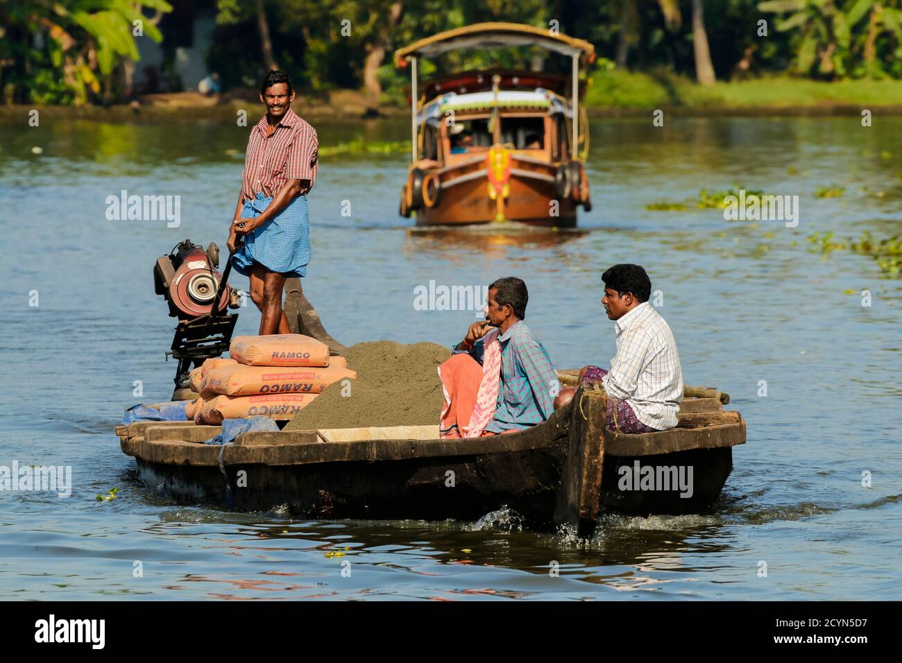 Workmen on small barge laden with cement for construction in a local ...