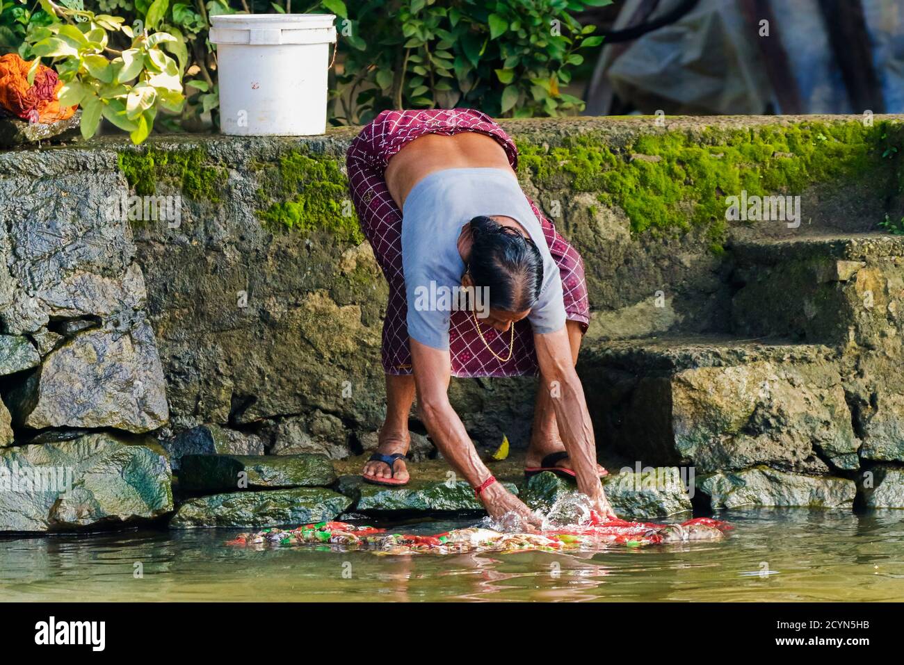 Woman washing clothes in traditional manner on the backwaters in this ...