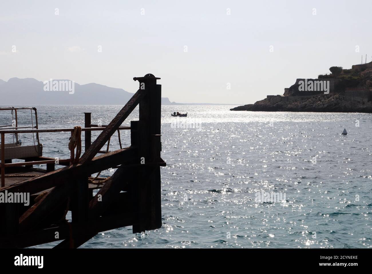 Silhouette outline of a jetty in harbor with bright sunlight sparkling ...