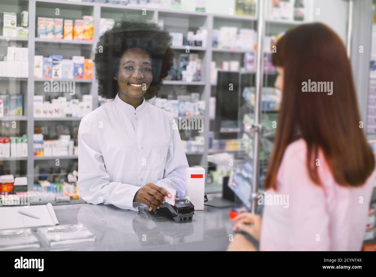 Caucasian woman customer making payment in drugstore. African woman ...