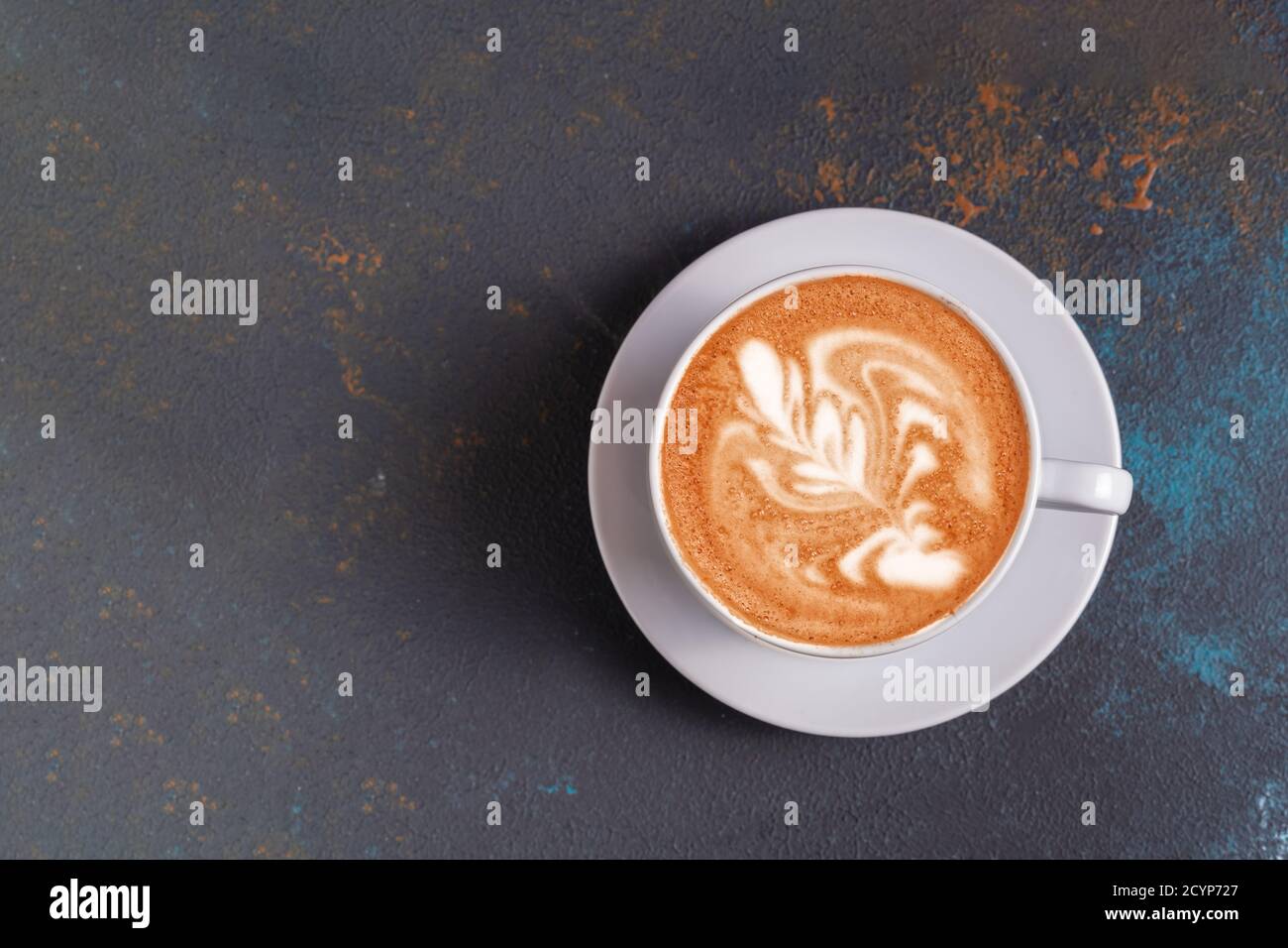 Flat lay latte art coffee with foam in cup on blue concrete background ...