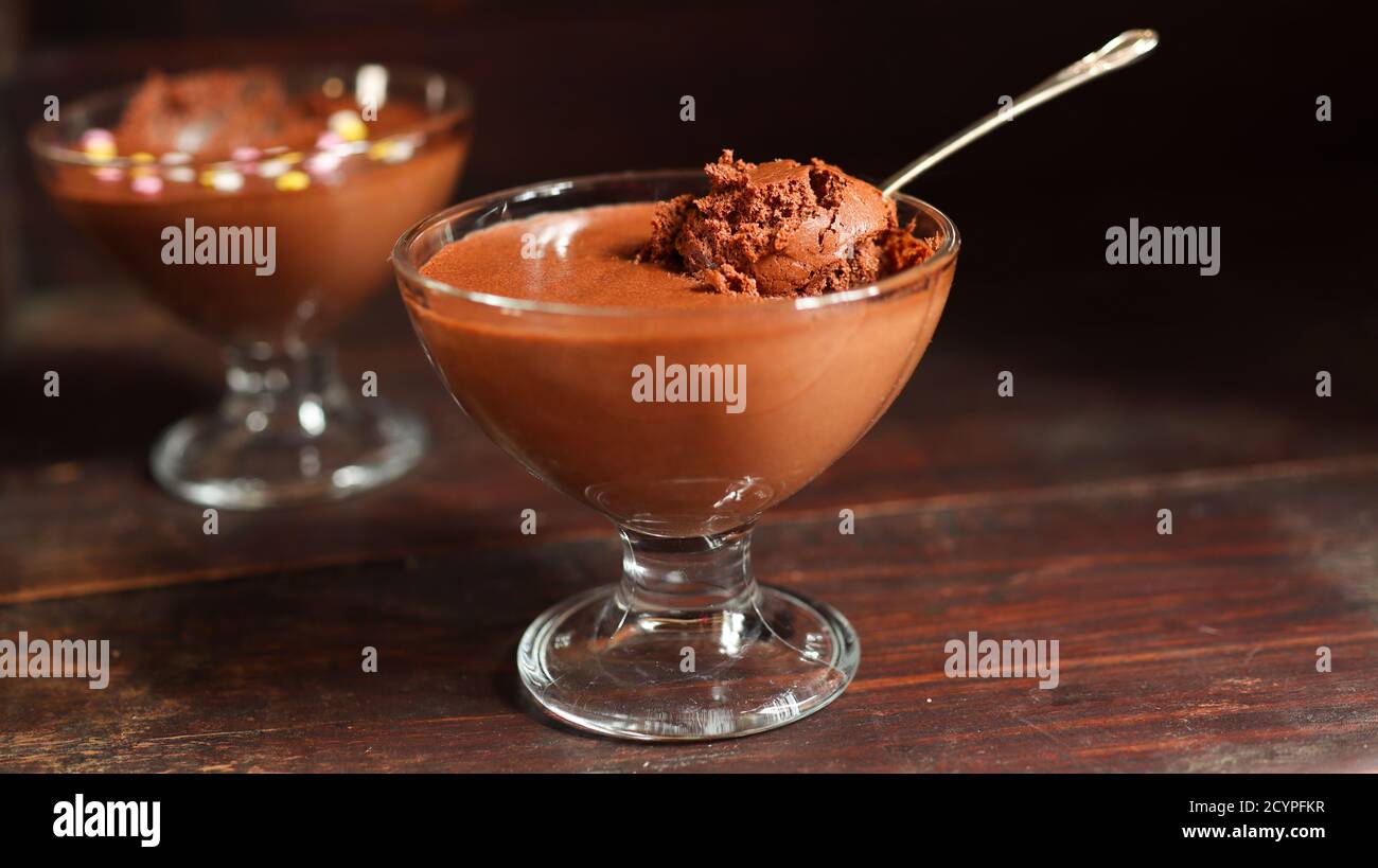 Chocolate mousse in transparent bowl close-up on the old dark brown ...