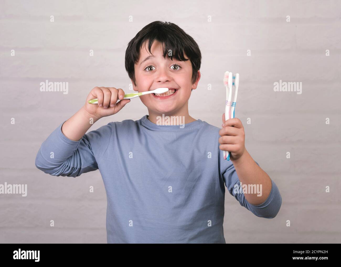 happy child cleaning teeth by toothbrush against brick background Stock ...