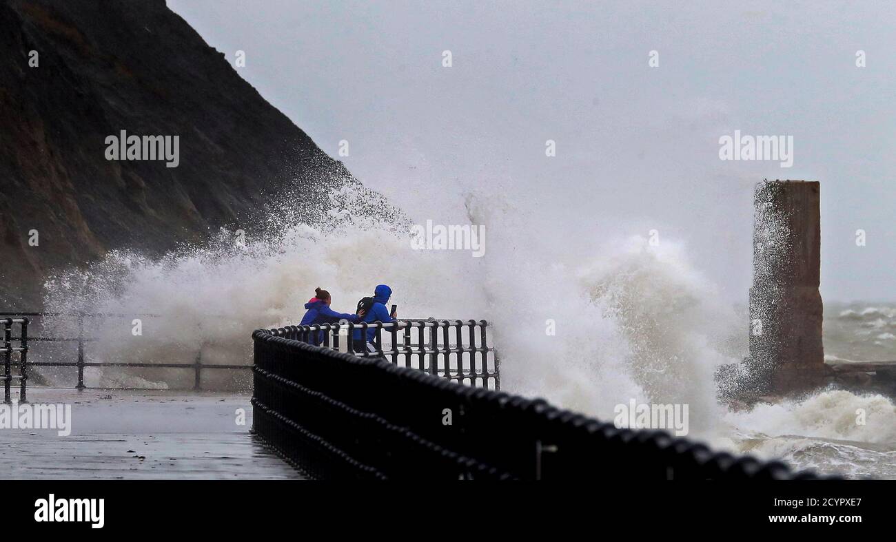 People take pictures of the waves hitting the harbour wall in ...