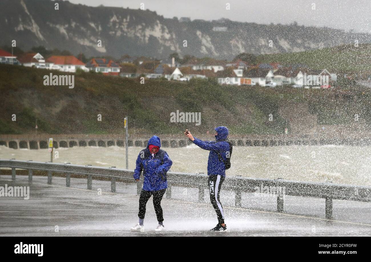 People take pictures of the waves hitting the harbour wall in ...
