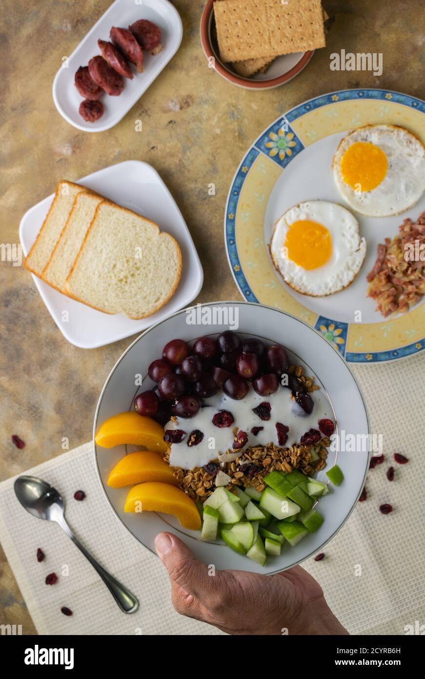 Overhead shot of a breakfast spread composed of eggs, fruits, bread ...