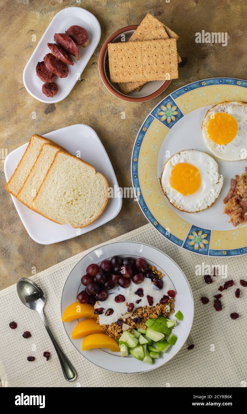 Overhead shot of a breakfast spread composed of eggs, fruits, bread ...