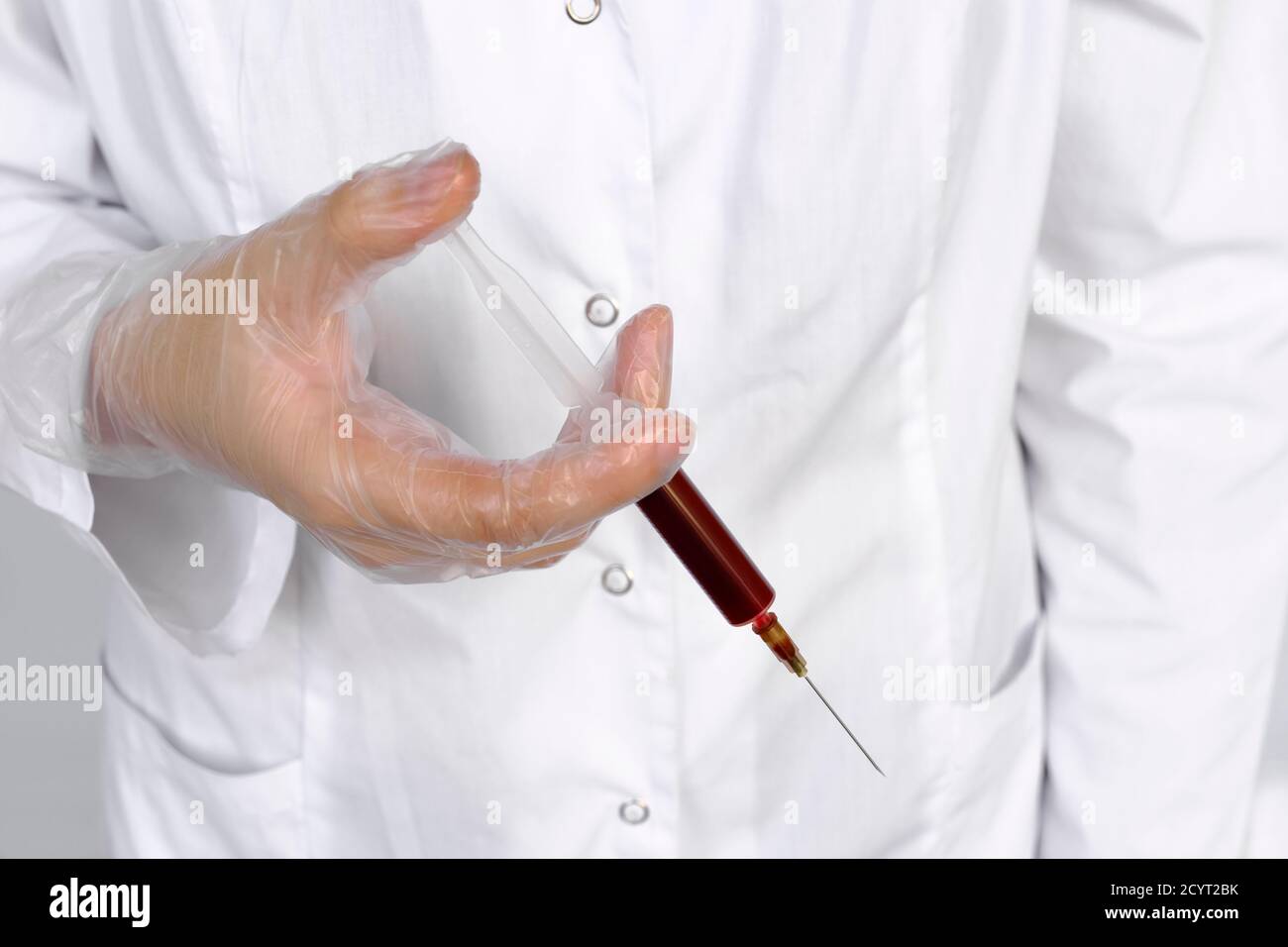 Doctor hand in a latex glove holds a syringe full of blood for analysis ...