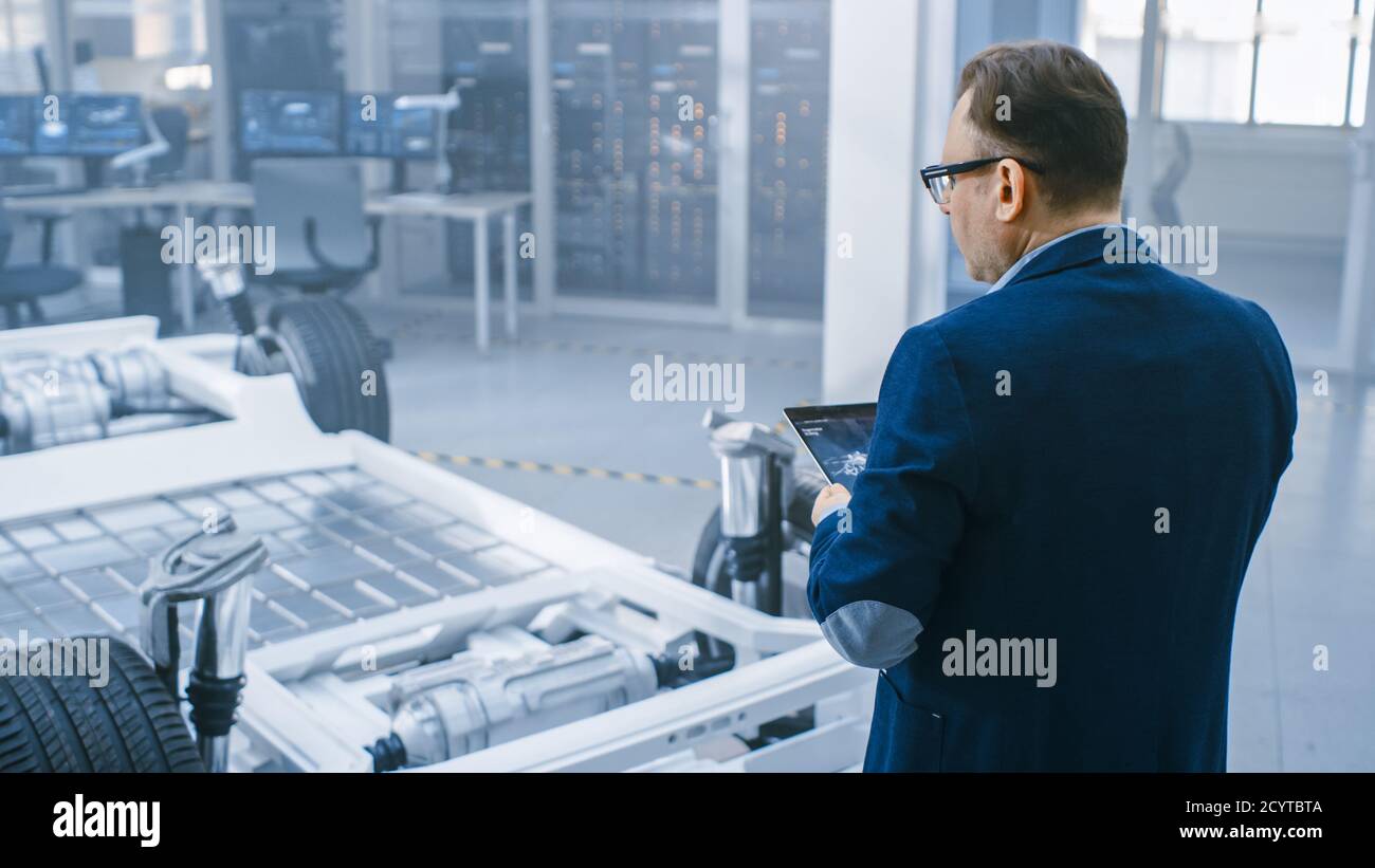 Automotive Design Engineer Looking at Technical Drawing of an Electric ...