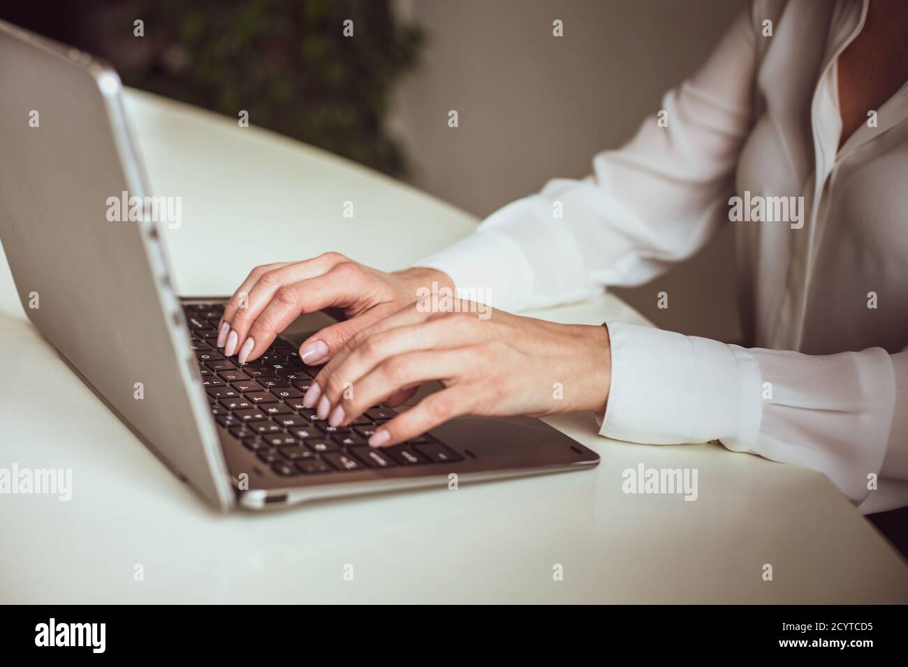Businesswoman working with laptop computer at white office desk. Side ...