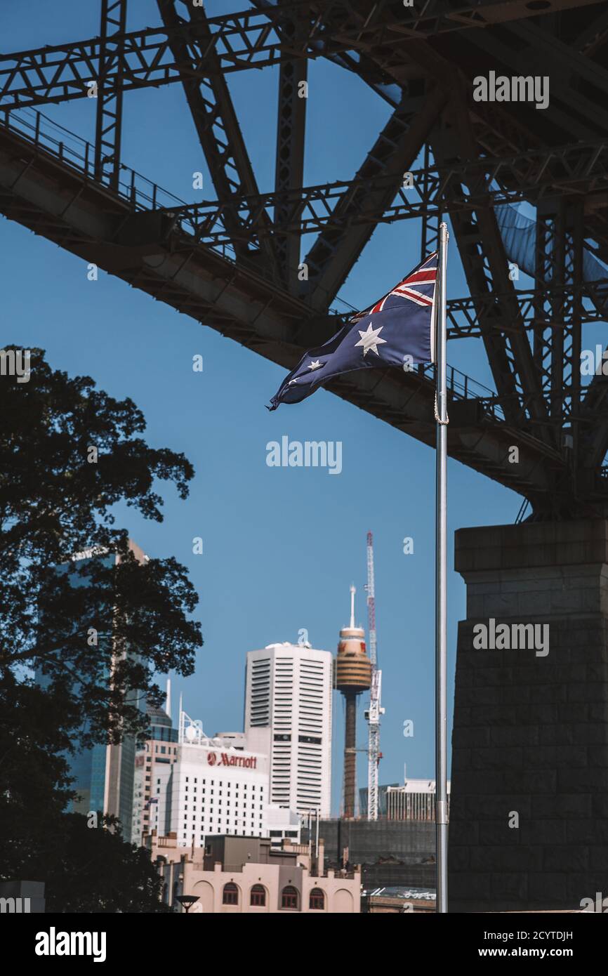 Vertical shot an Australian flag under a bridge and view of skyscrapers ...