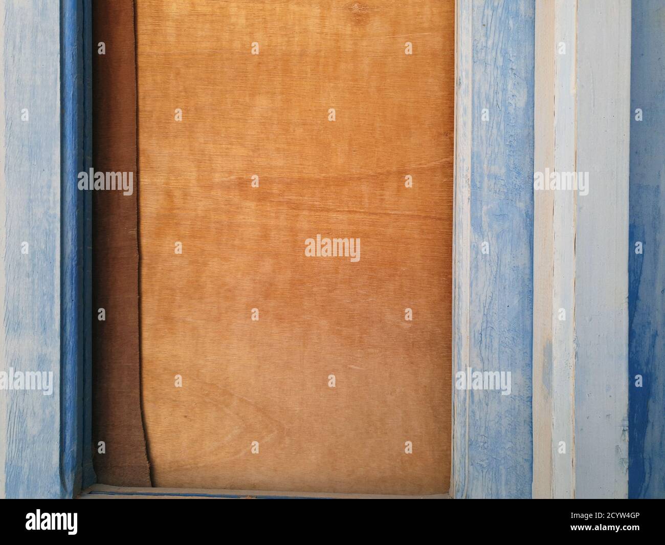 Brown plywood embedded in a blue wood window frame Stock Photo - Alamy