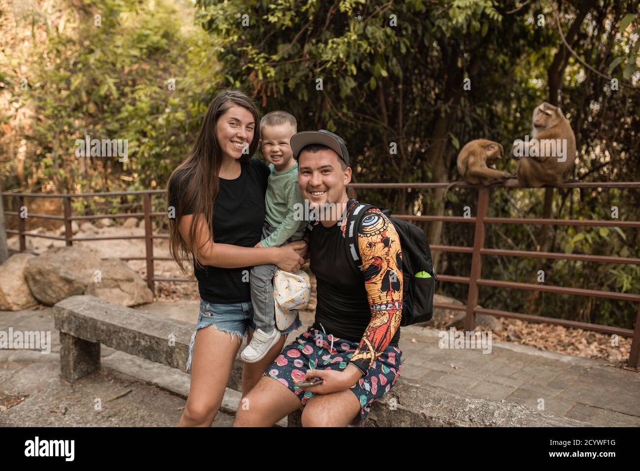 Monkeys are sitting behind people family with a child Stock Photo - Alamy