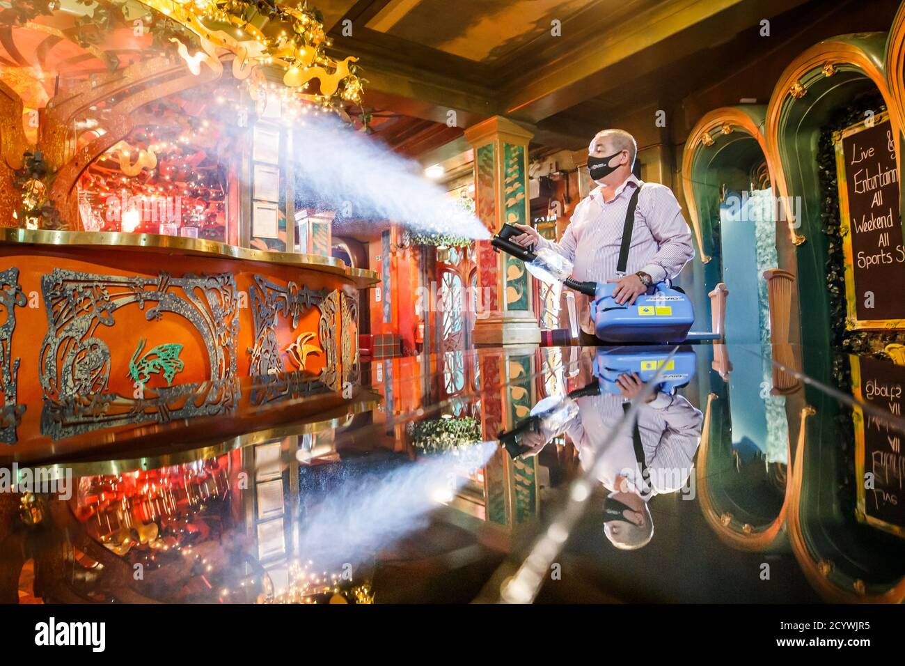 Mark Cummins using a misting and fogging machine to clean and disinfect ...