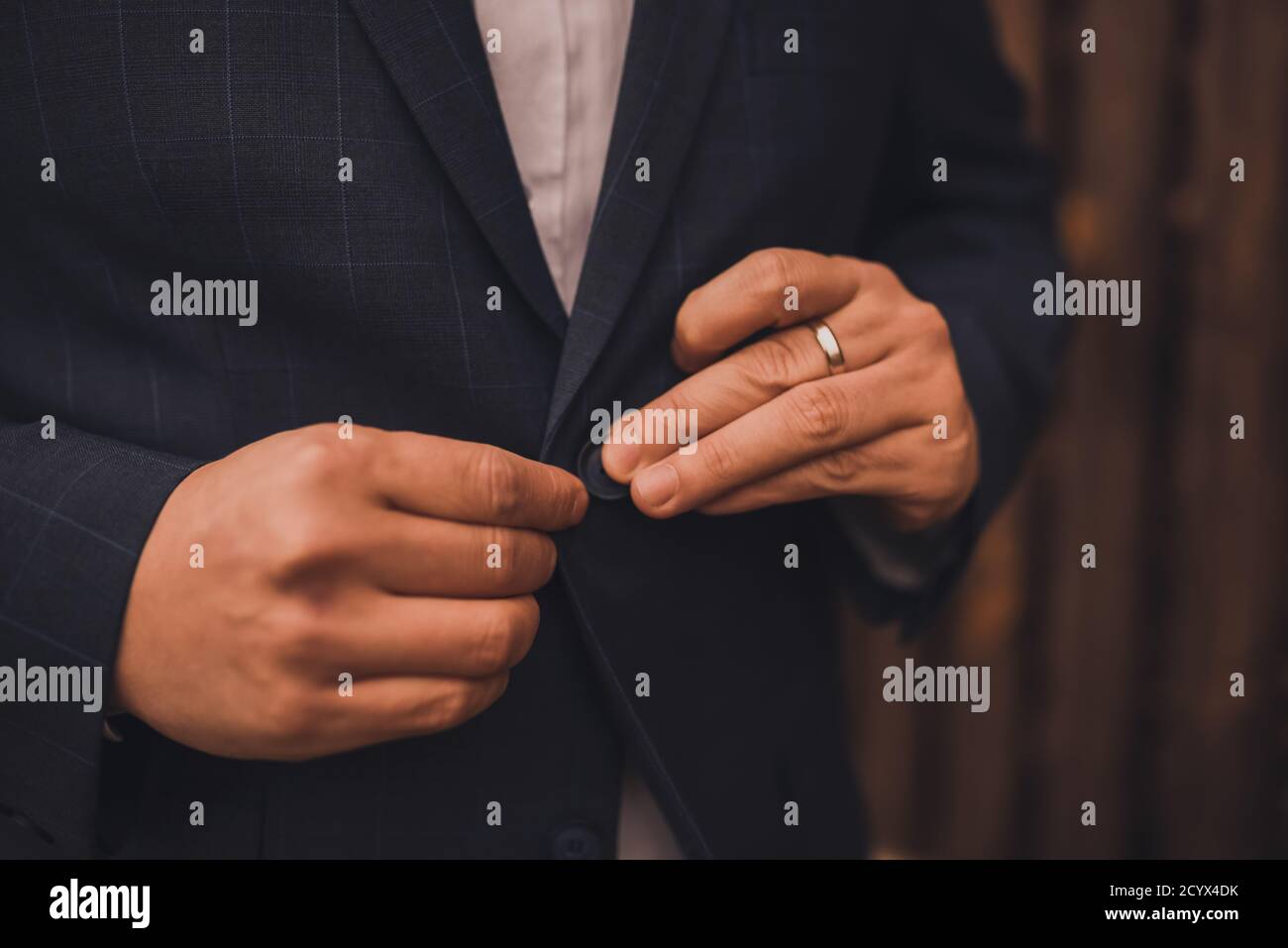 A man in a dark business suit buttoning a button on jacket Stock Photo ...
