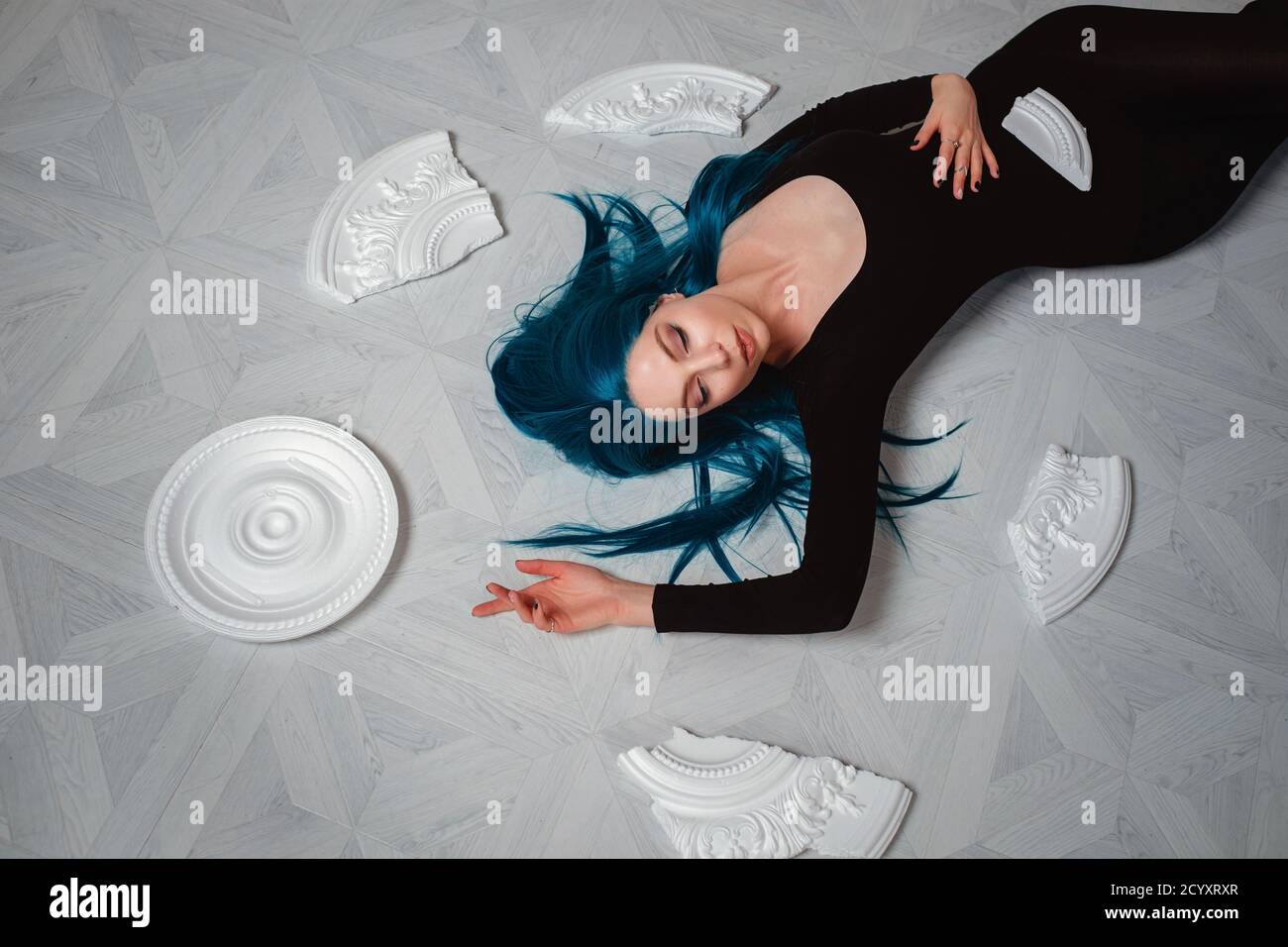 A beautiful young woman with blue hair posing in an art studio or ...