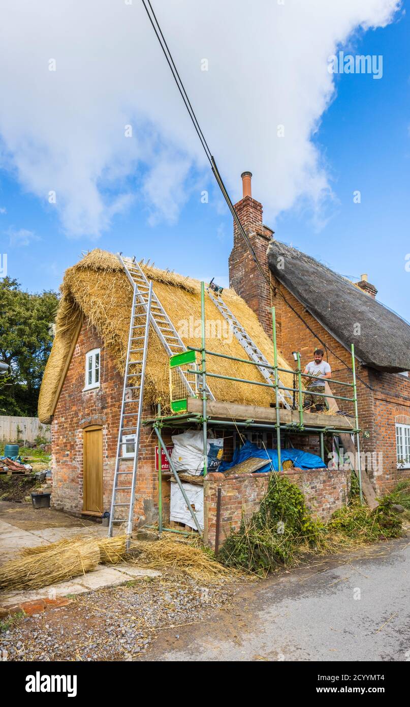 A skilled thatcher at work replacing the traditional thatched roof of ...