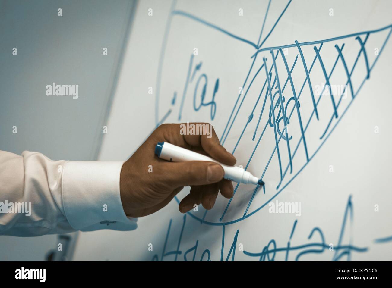 Male hand draws with marker diagram on white board. Toned image. Close ...