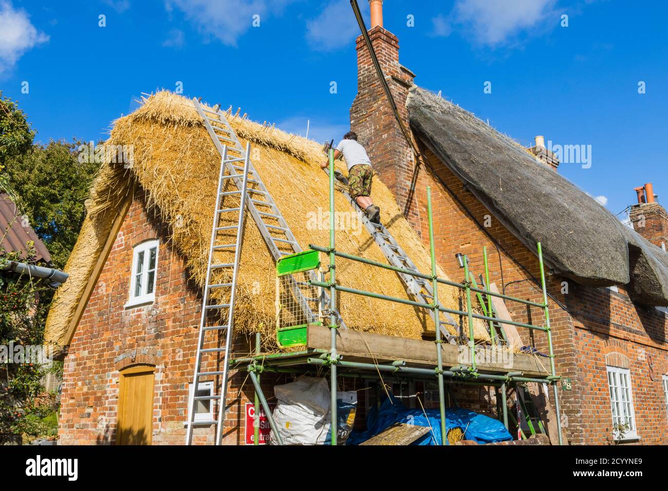A skilled thatcher at work replacing the traditional thatched roof of ...