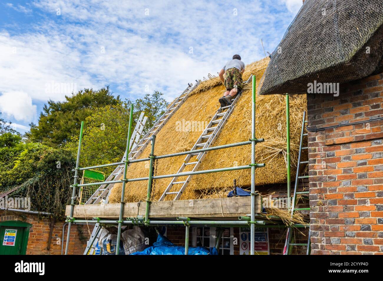 A skilled thatcher at work replacing the traditional thatched roof of ...