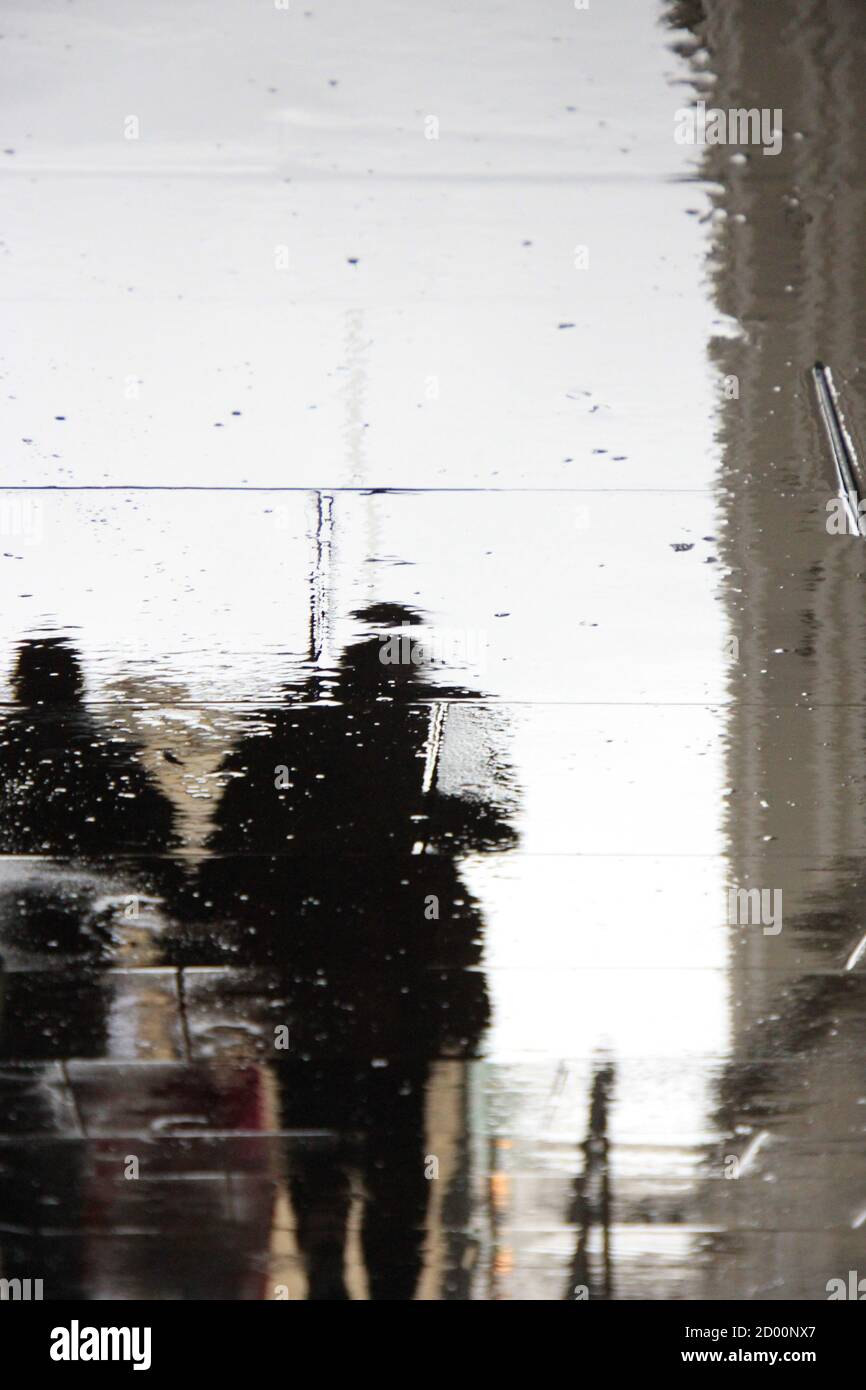 Reflection on pavement of car and people walking on the street Stock ...