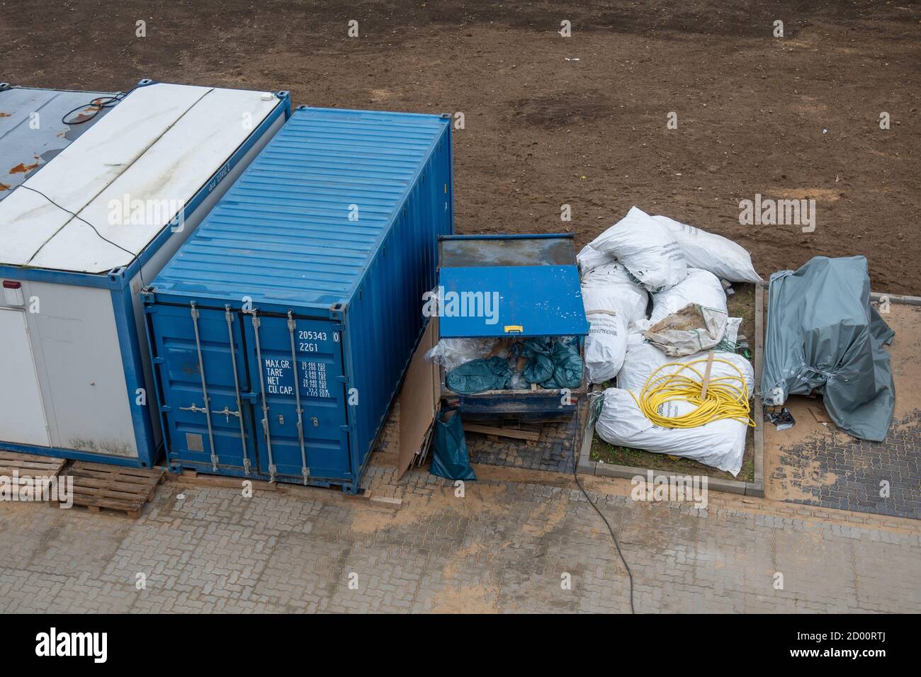 blue and white construction containers stand next to a waste container ...