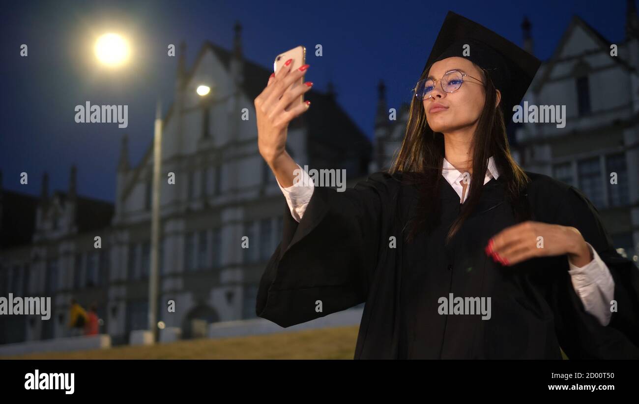 Cute graduate girl preening using her phone Stock Photo - Alamy