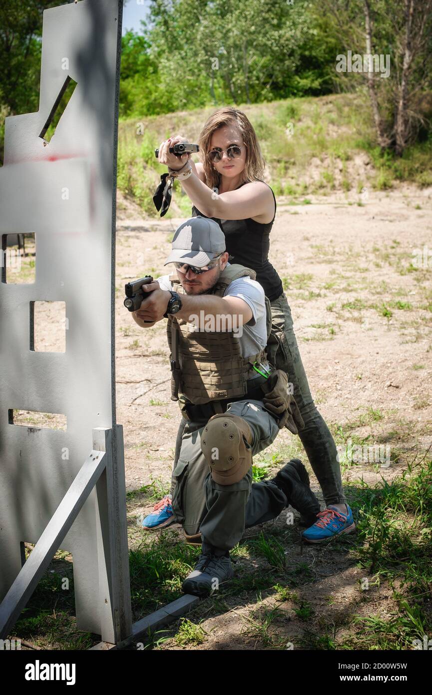 Instructor on shooting range teaches his female student tactical gun ...