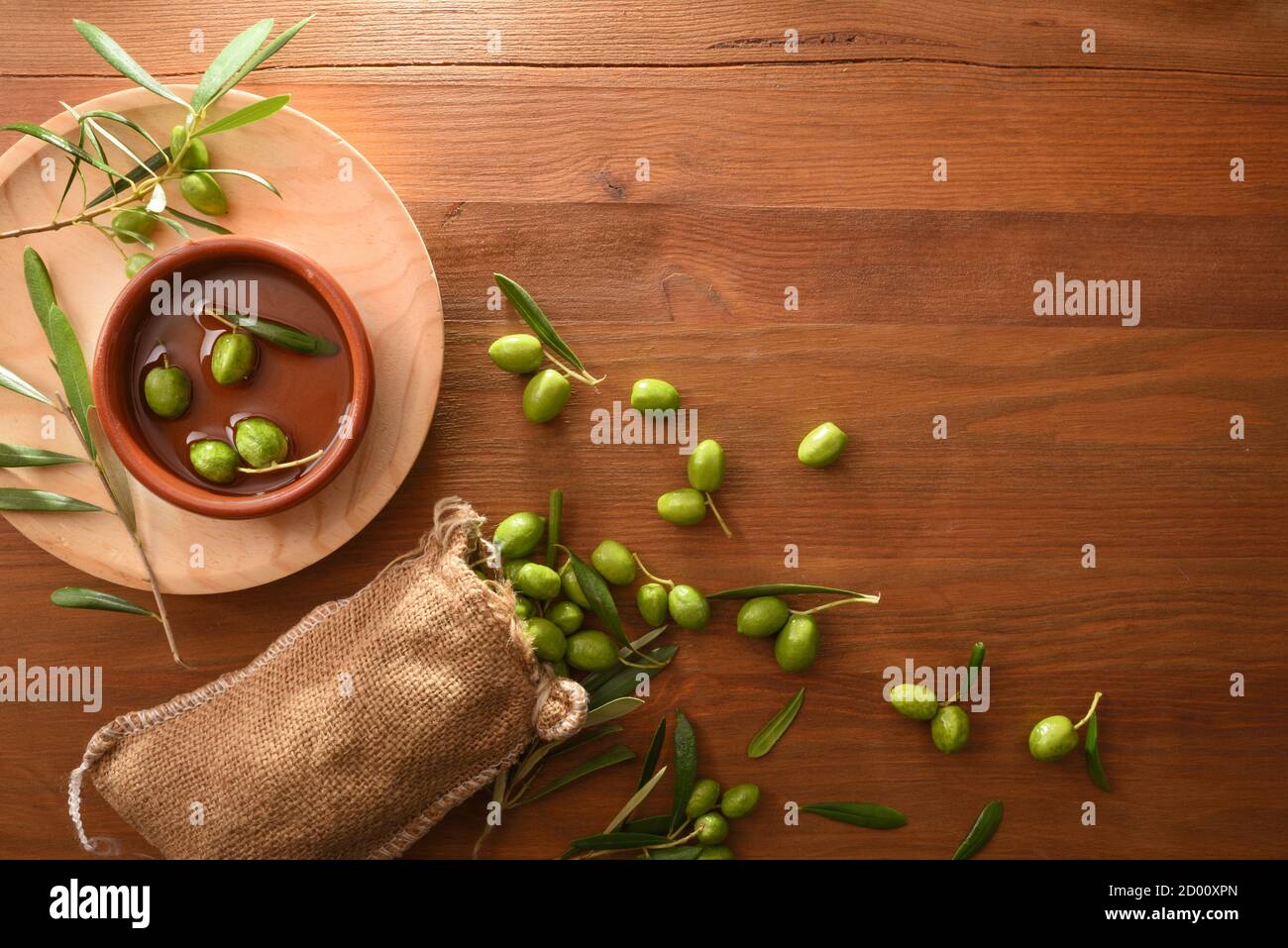 Sack of harvest raw olives on wooden table with leaves and containers ...