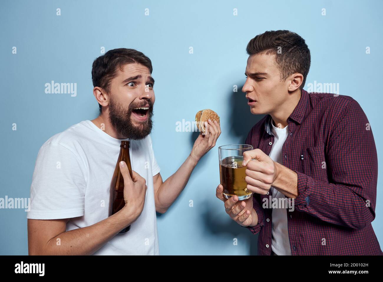 Two cheerful drunk friends drinking beer lifestyle emotions on a blue ...