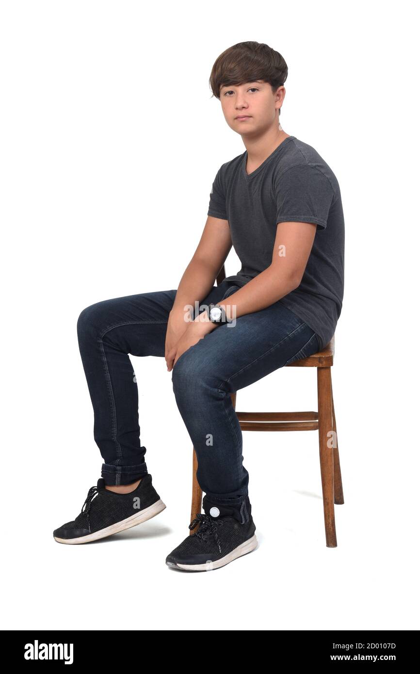 teenage boy sitting on a chair with white background, serious and ...