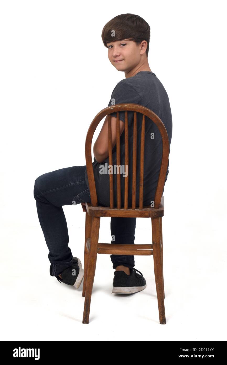rear view of teenage boy sitting on a chair with white background ...
