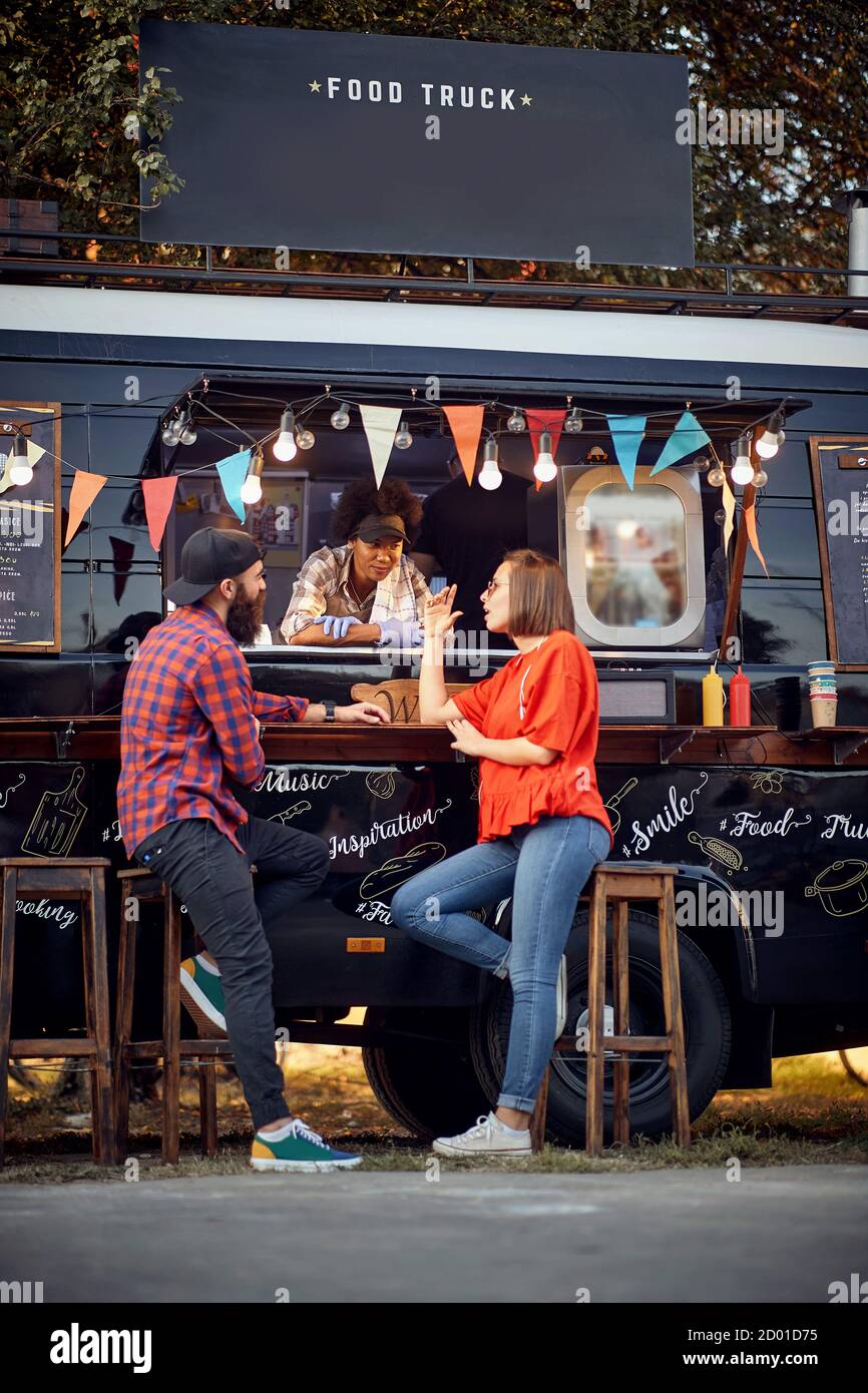 Hipster couple ordering from food truck on the street; Urban lifestyle ...