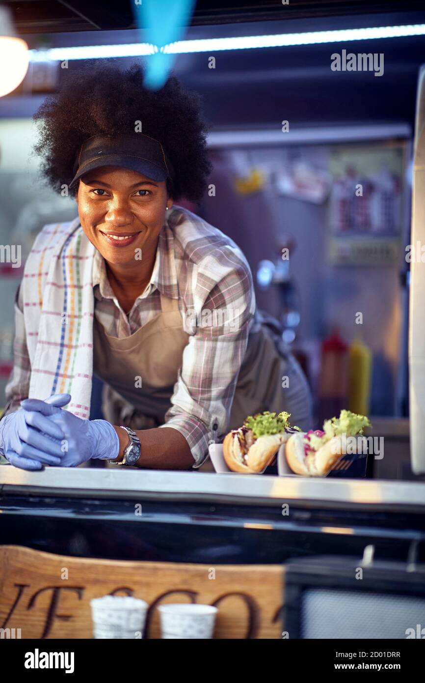 Cheerful afro american food truck employee taking orders from customers ...