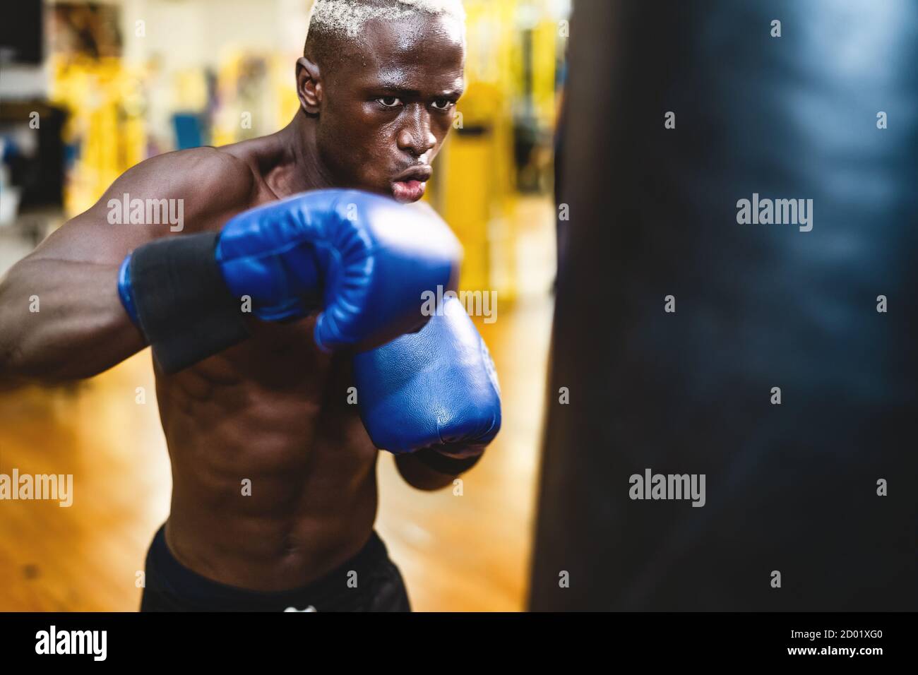 Man boxer training hard - Young black guy boxing in sport gym center ...