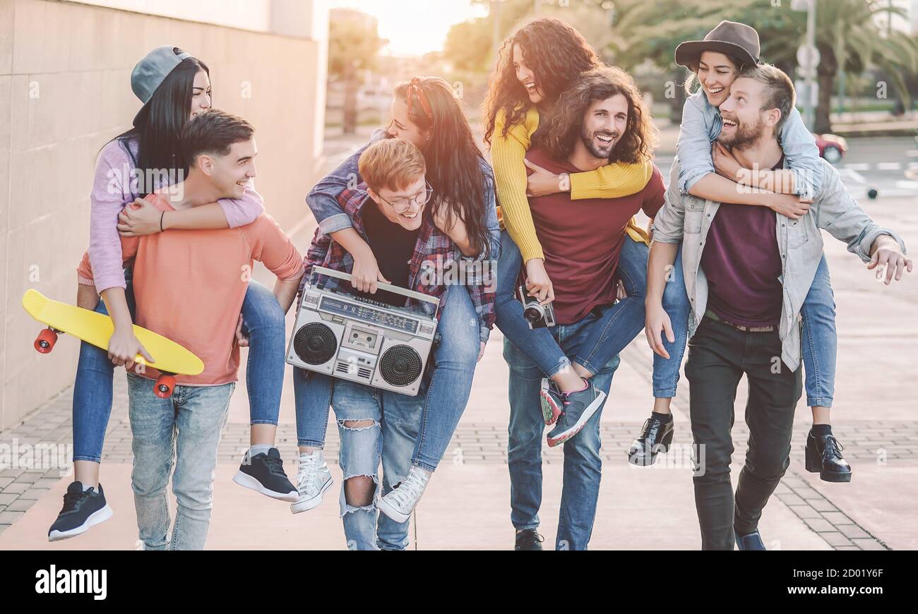 Happy friends having fun walking piggyback in the city center - Group ...