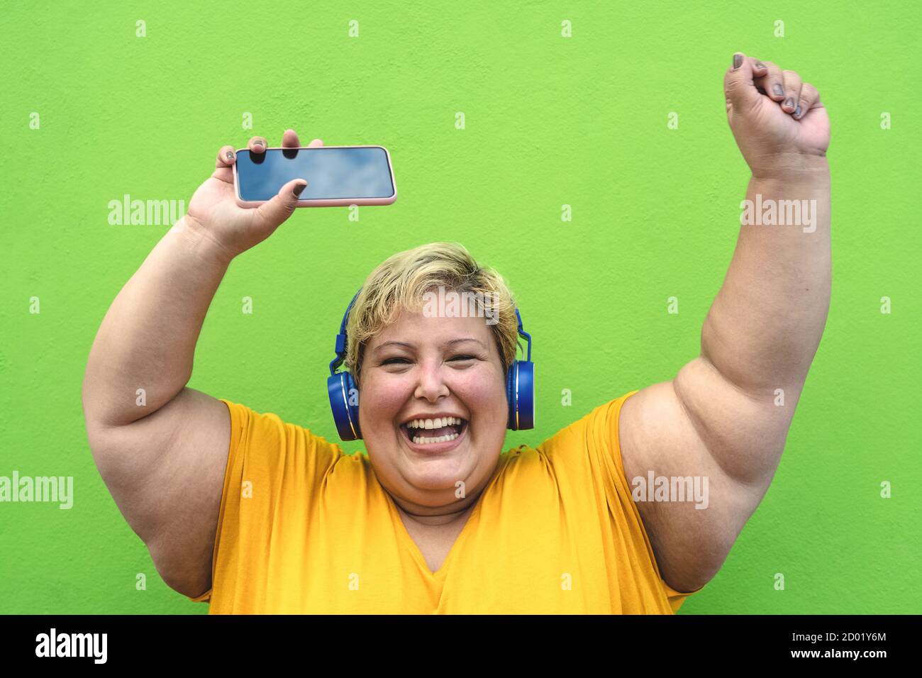 Happy plus size woman listening music with mobile smartphone and ...