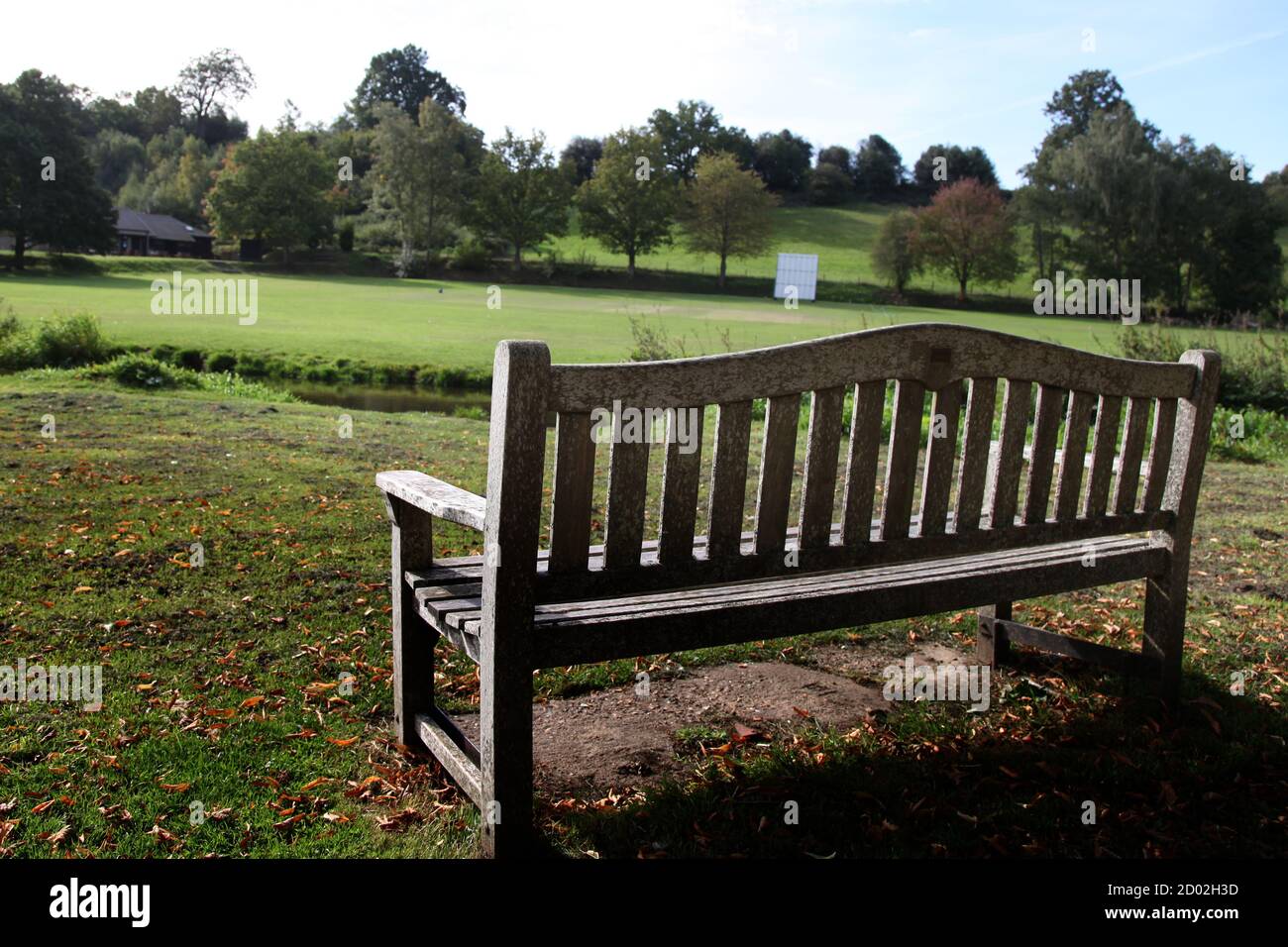 A single empty park bench on the riverbank of Tillingbourne River ...