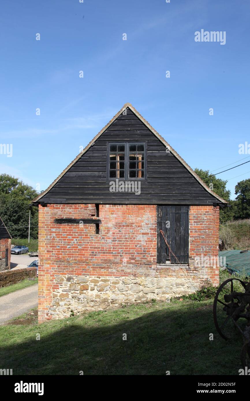 A barn at Paddington Mill Farm against blue sky, located in the village ...