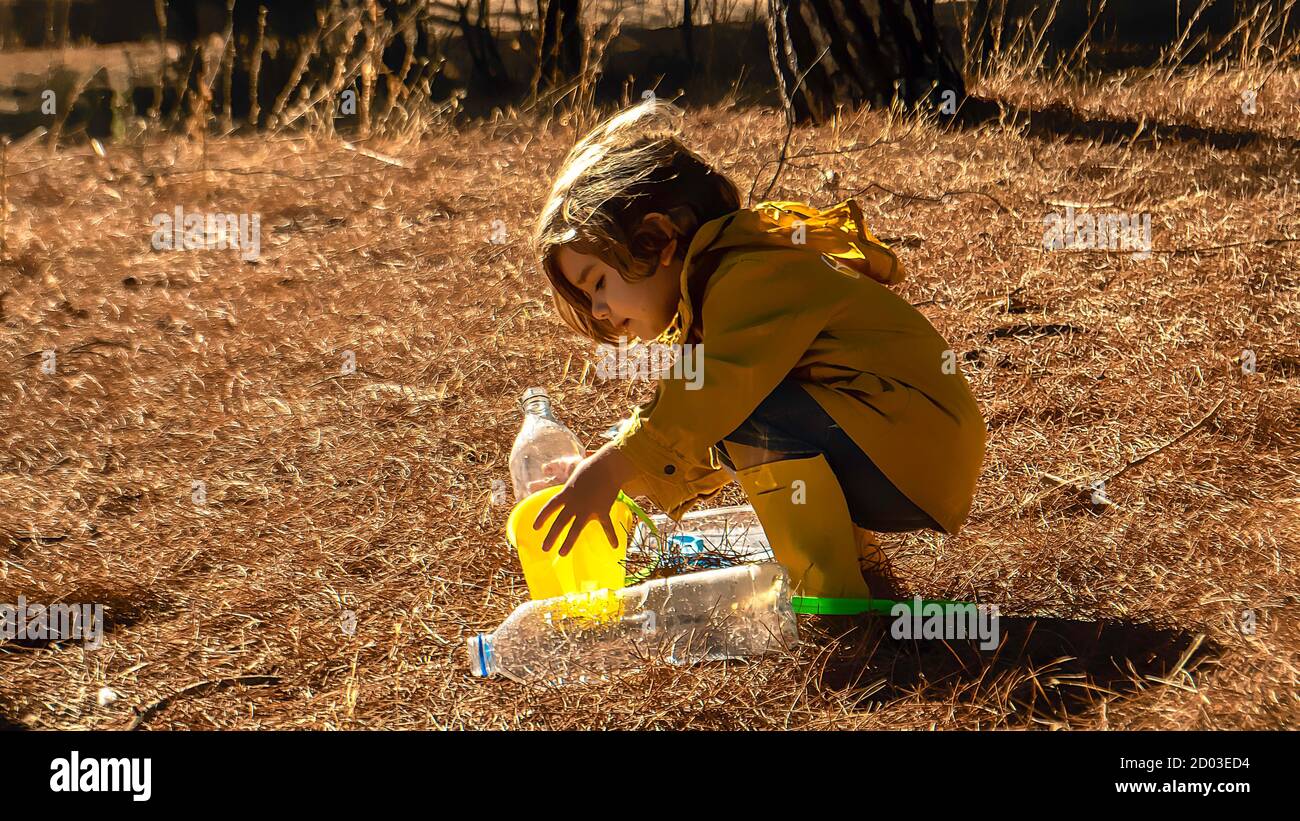 Young child is picking up plastic waste in the forest as a volunteer ...