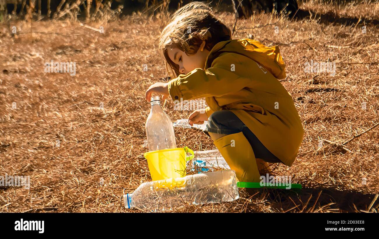 Young child is picking up plastic waste in the forest as a volunteer ...